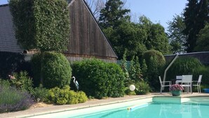 Piscina com estrutura de madeira e vegetação ao fundo.