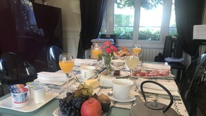Mesa de café da manhã com diversos alimentos, copos de suco de laranja e um bule.