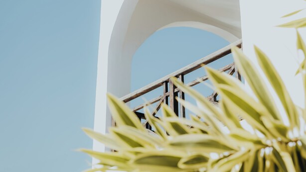 Um edifício branco com varanda e céu azul claro ao fundo.