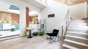 Um interior moderno com escada, parede de tijolos e área de estar com mesa e cadeiras.