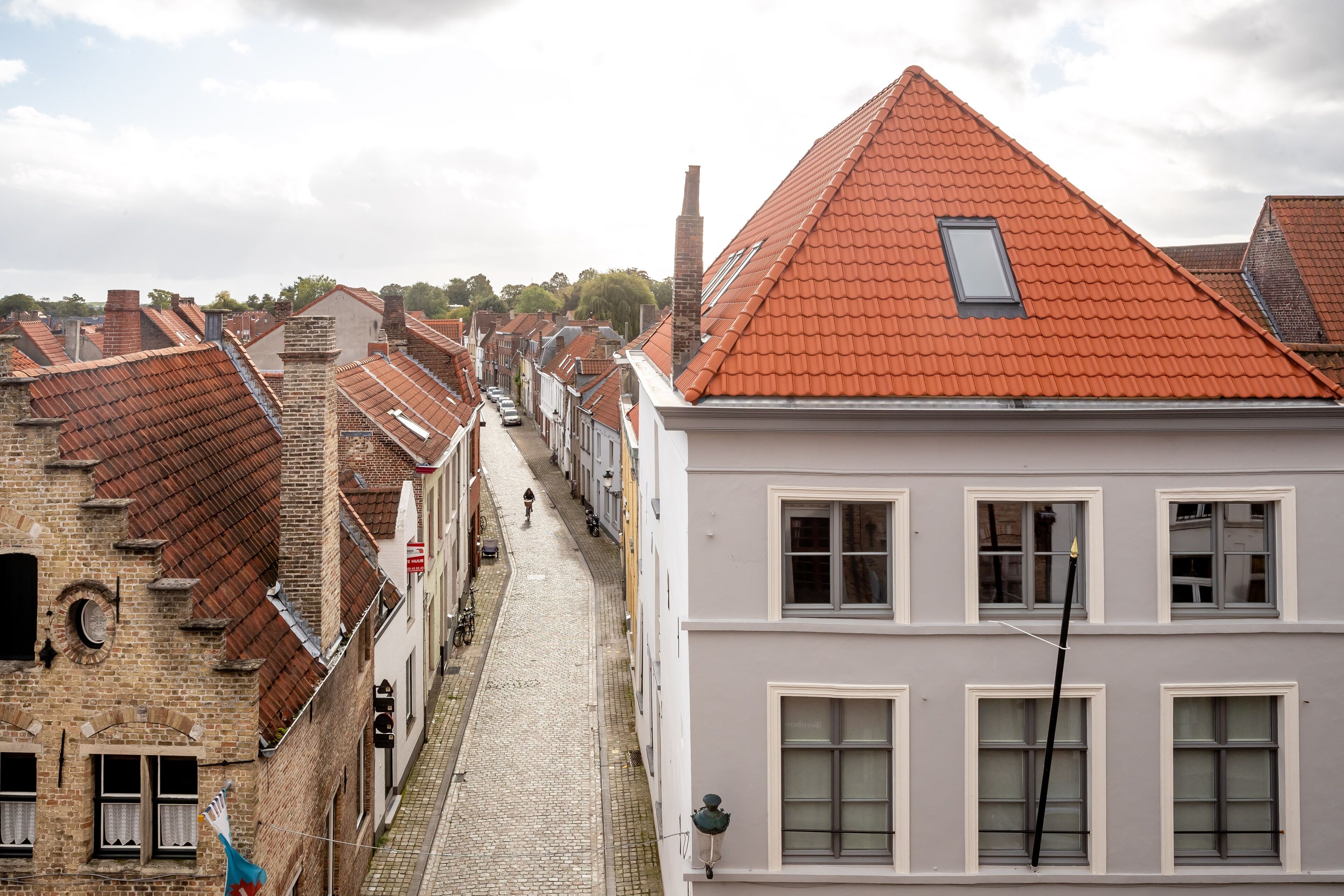 Uma rua de paralelepípedos estreita, ladeada por edifícios históricos com telhados vermelhos e arquitetura tradicional.
