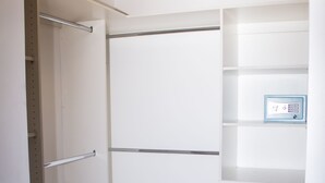 Um closet espaçoso com prateleiras abertas, uma barra para pendurar roupas e um pequeno aparelho eletrônico na prateleira superior.