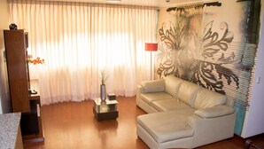 Uma sala de estar com um sofá bege, um armário de madeira e um abajur.