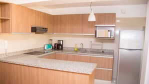 Uma cozinha moderna com bancadas de granito, armários de madeira e eletrodomésticos de aço inoxidável, incluindo micro-ondas embutido.