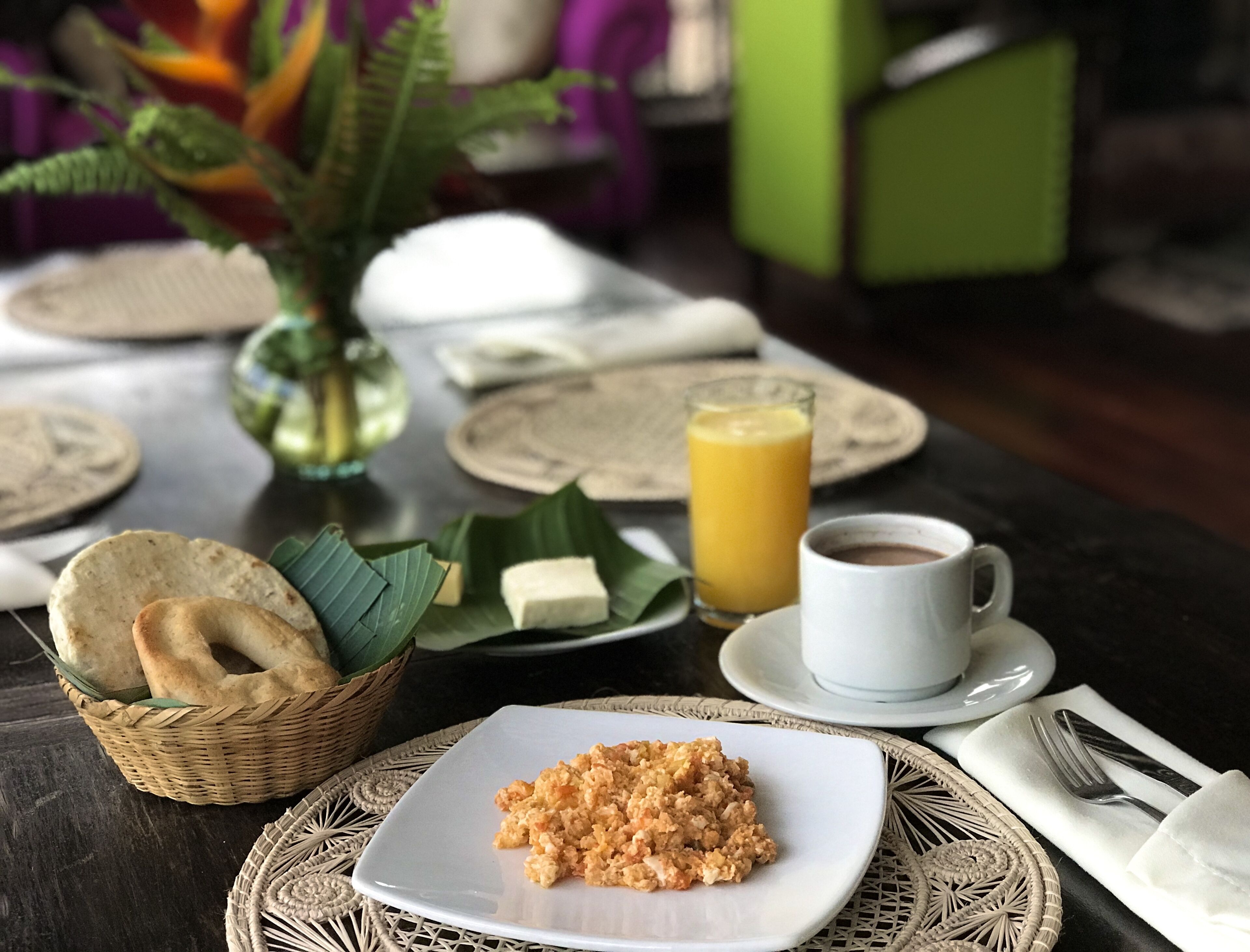 Mesa com tigela de cereal, xícara de café e copo de suco de laranja.