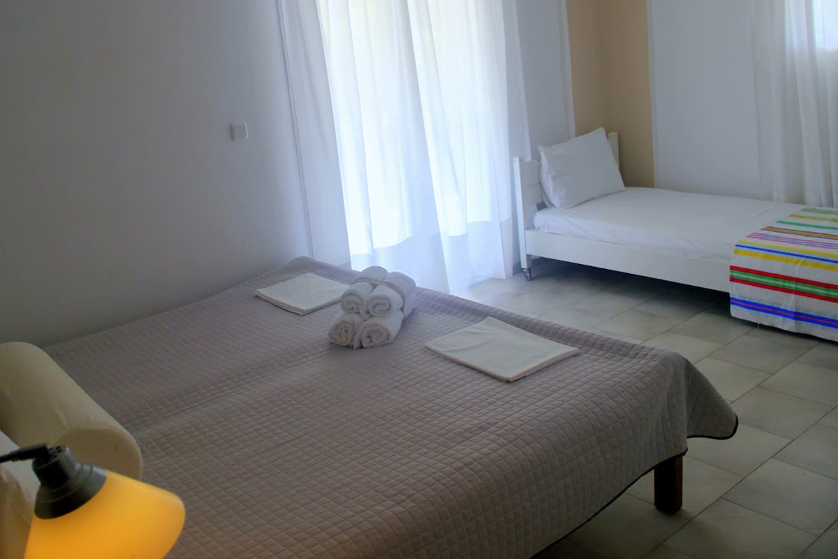 Quarto de hotel com cama, sofá e abajur.