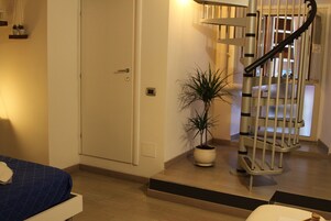 Quarto com cama, planta em vaso, escada e porta.