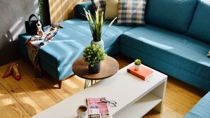 Uma sala de estar moderna com um sofá azul, uma mesa de centro e uma pequena estante.