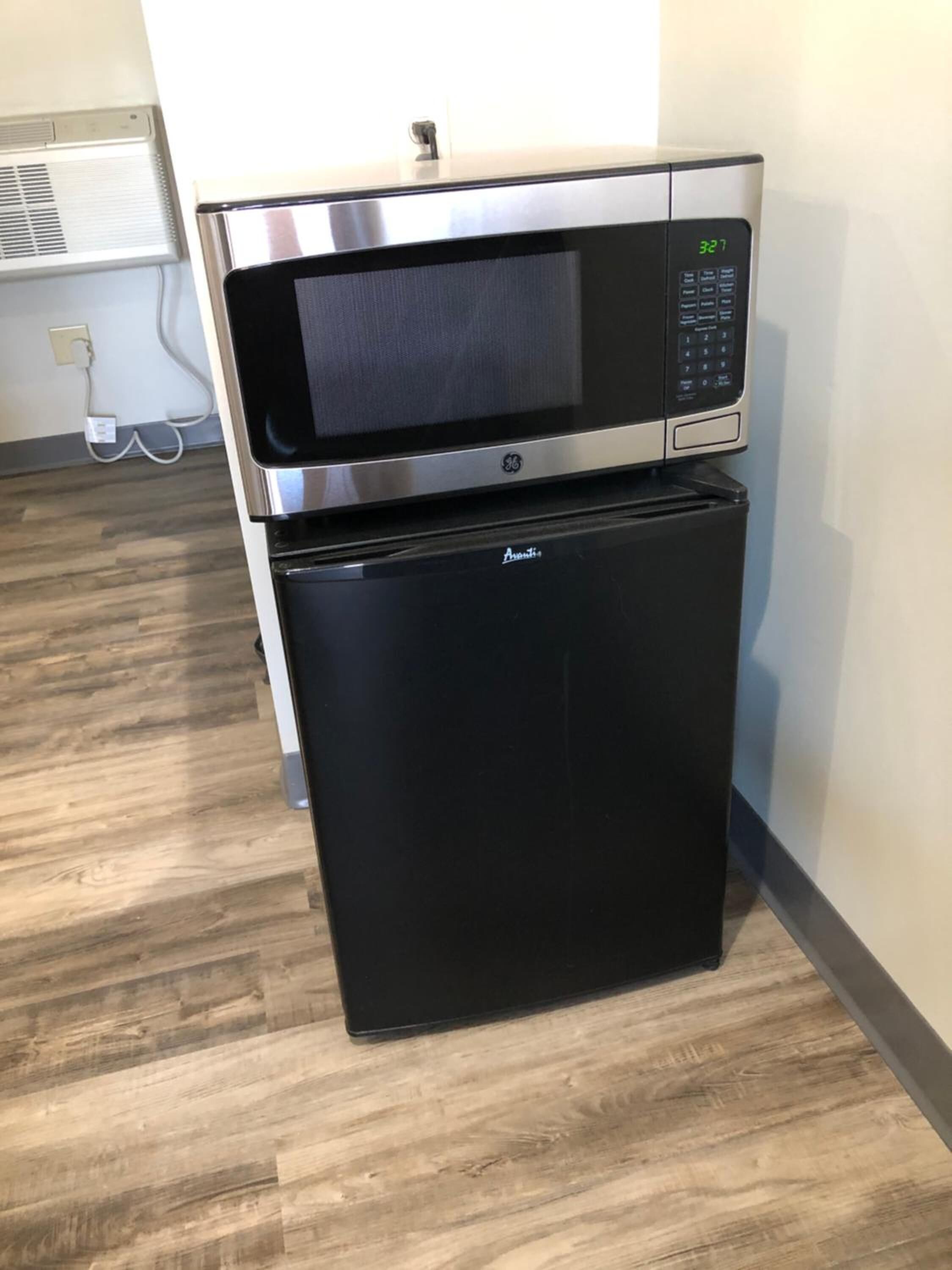 Uma cozinha compacta com micro-ondas e frigorífico de aço inoxidável.