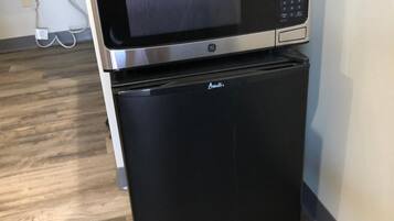 Uma cozinha compacta com micro-ondas e frigorífico de aço inoxidável.