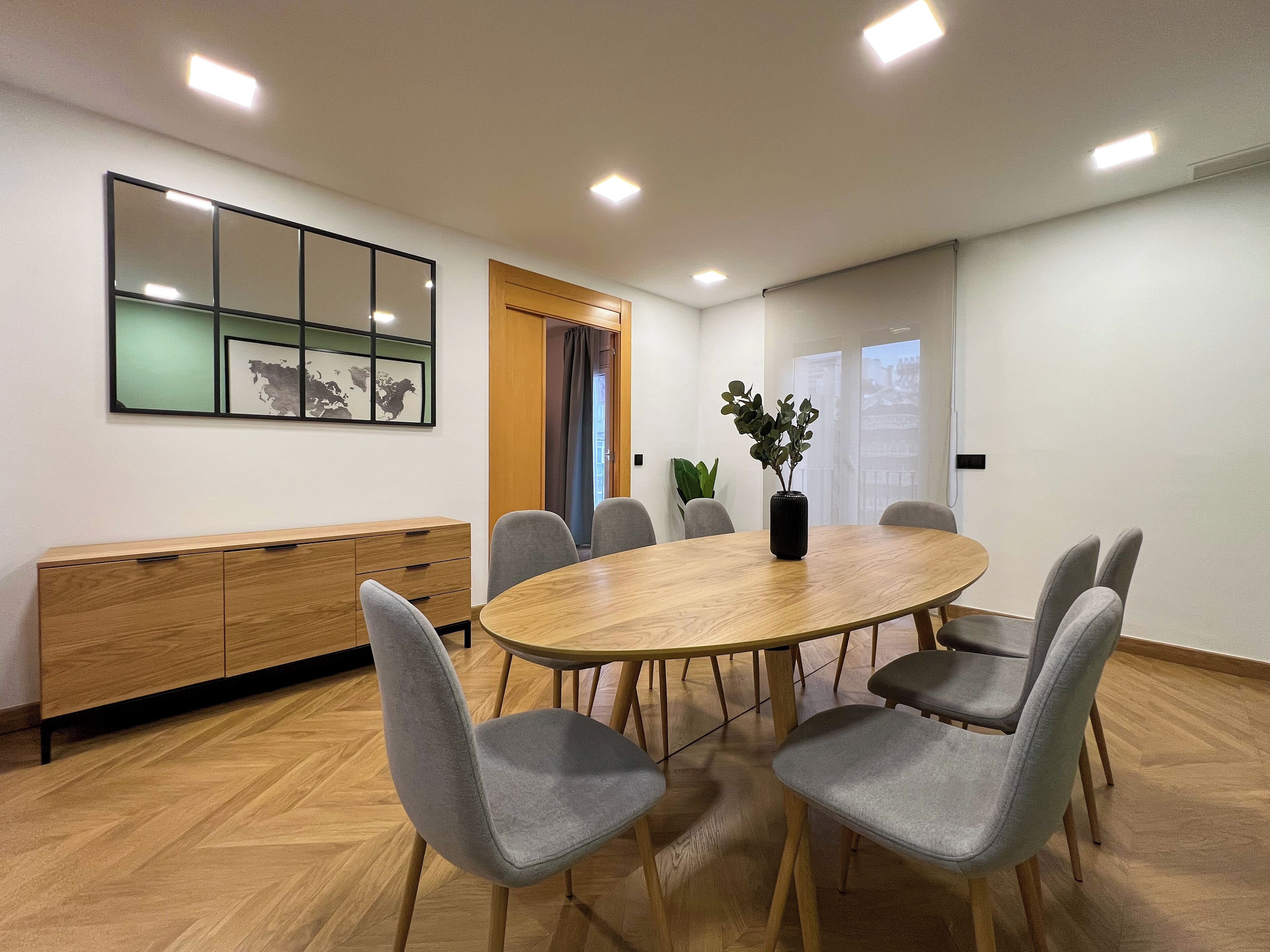 Uma sala de conferências com mesa de madeira, cadeiras estofadas cinzas, um banco de madeira e um mapa-múndi na parede.