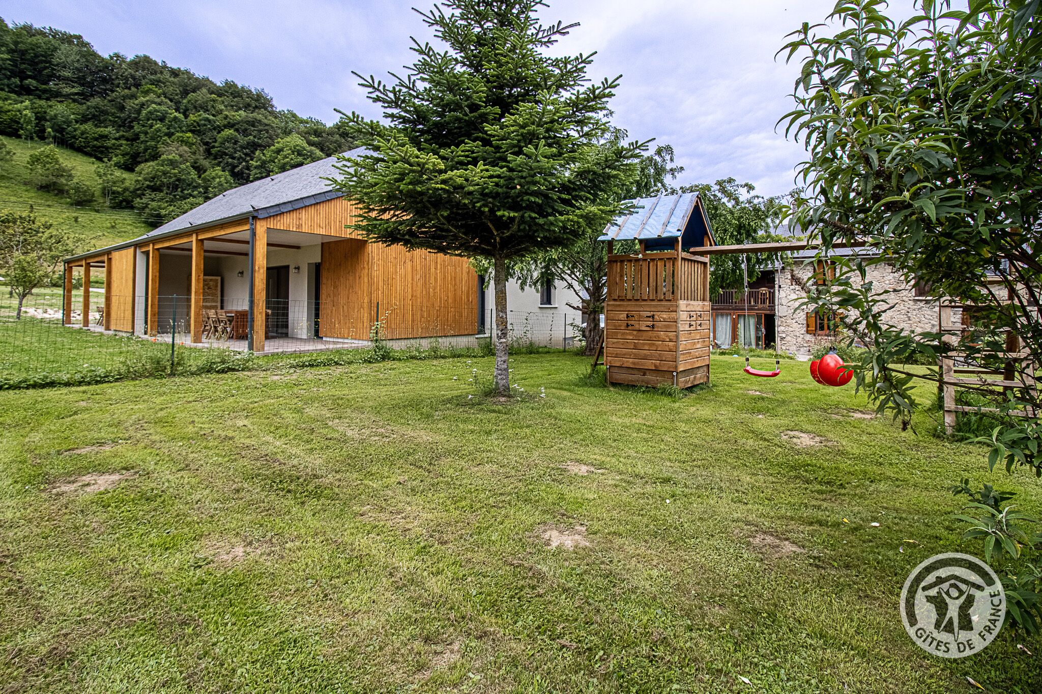 Uma casa moderna com fachada de madeira, um alpendre coberto e um pequeno jardim.