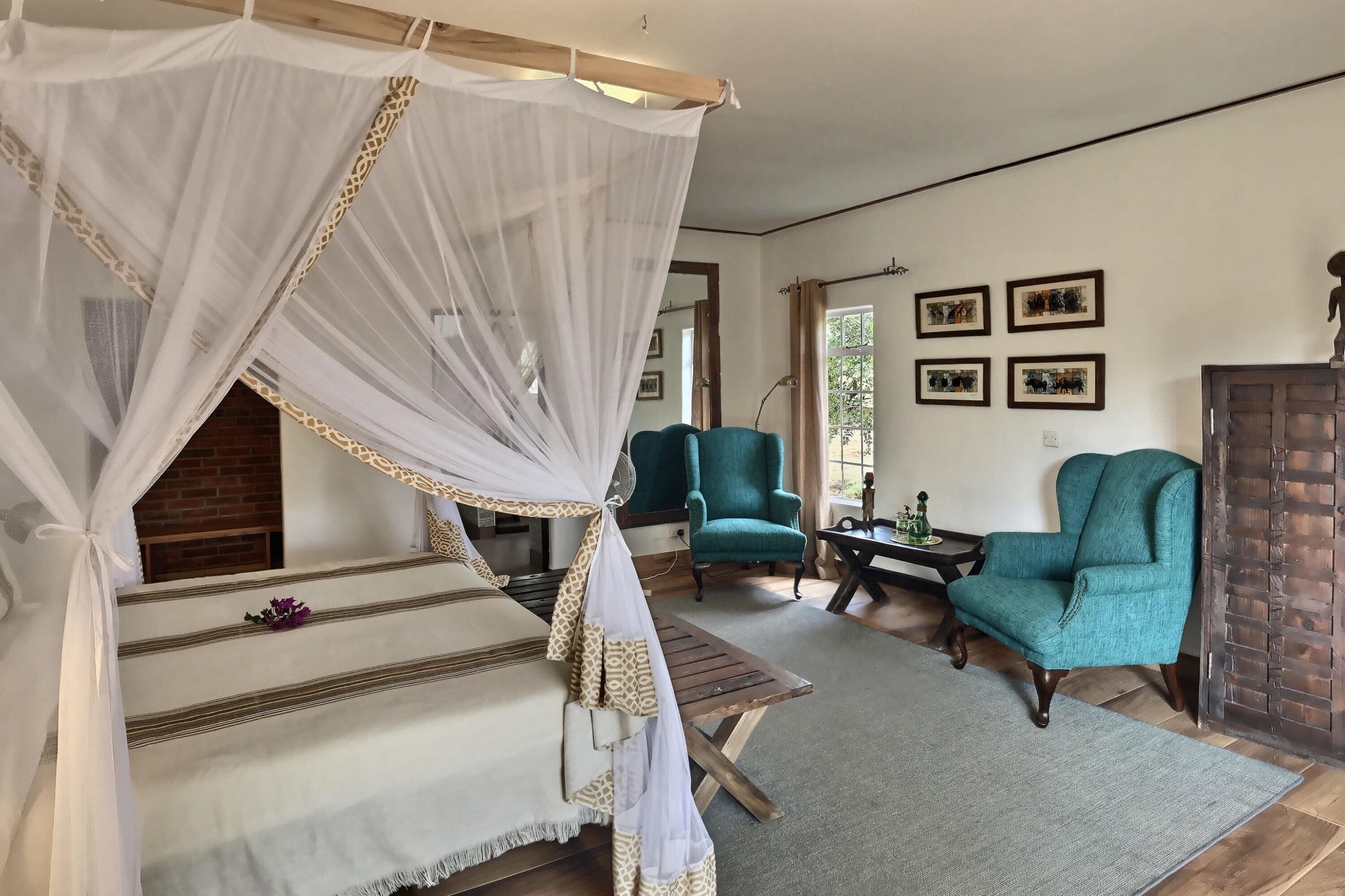 Quarto com cama, poltrona verde, mesa de madeira e tapete pequeno.