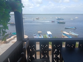 Vista de um corpo d'água com vários barcos, uma varanda com guarda-corpo e um vaso de planta.