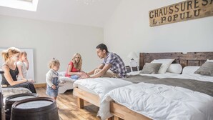Uma família num quarto com uma cama, cabeceira de madeira e um aviso na parede.