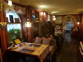 Um quarto acolhedor com uma mesa de madeira, um sofá e um espelho decorativo. Há vários objetos na mesa e nas prateleiras, incluindo um vaso e uma luminária.
