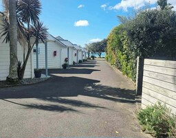 Fileira de casas móveis brancas, com um caminho de acesso pavimentado e uma cerca de madeira de um lado.