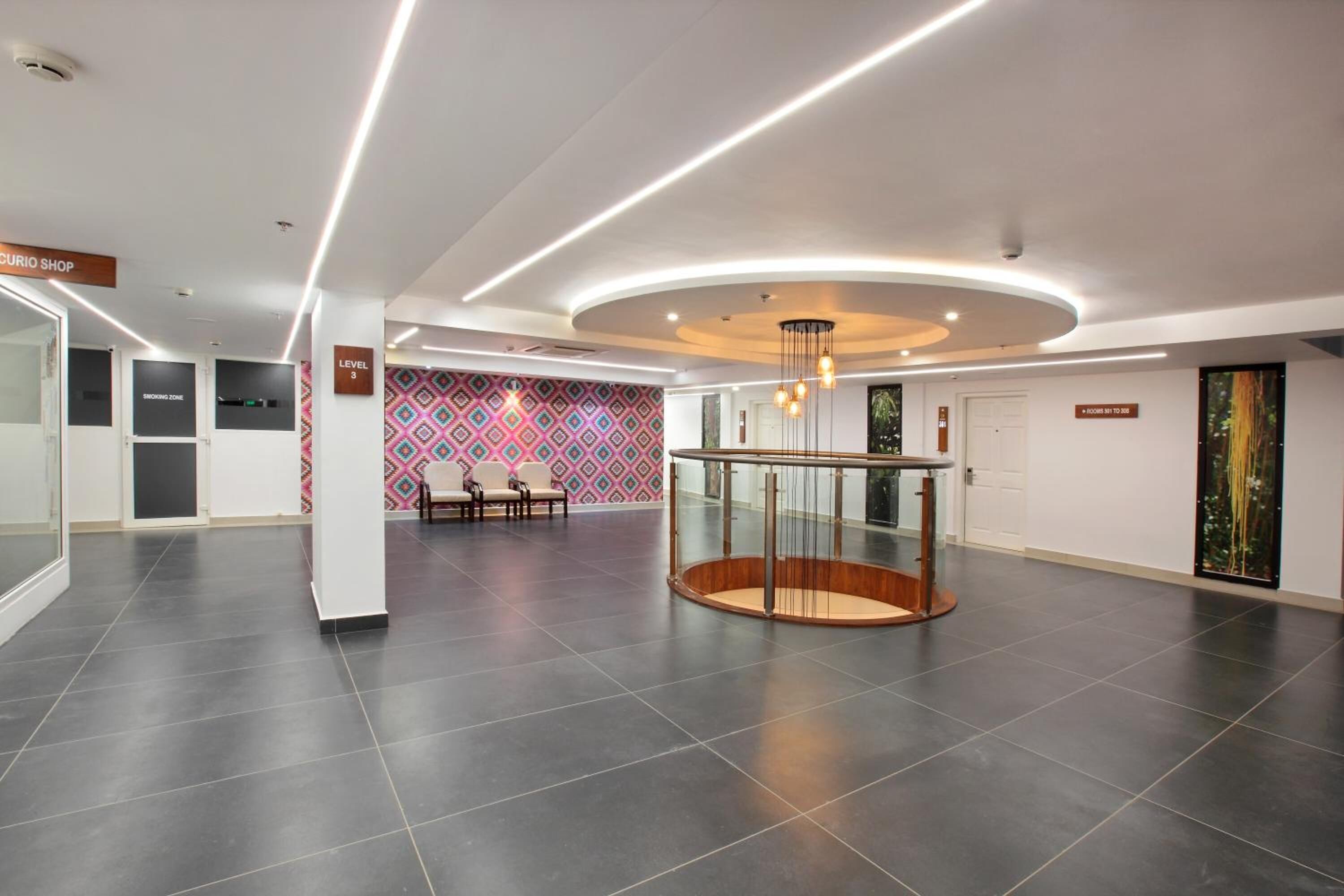 Um lobby moderno com uma mesa de vidro central, área de estar e parede com padrão.