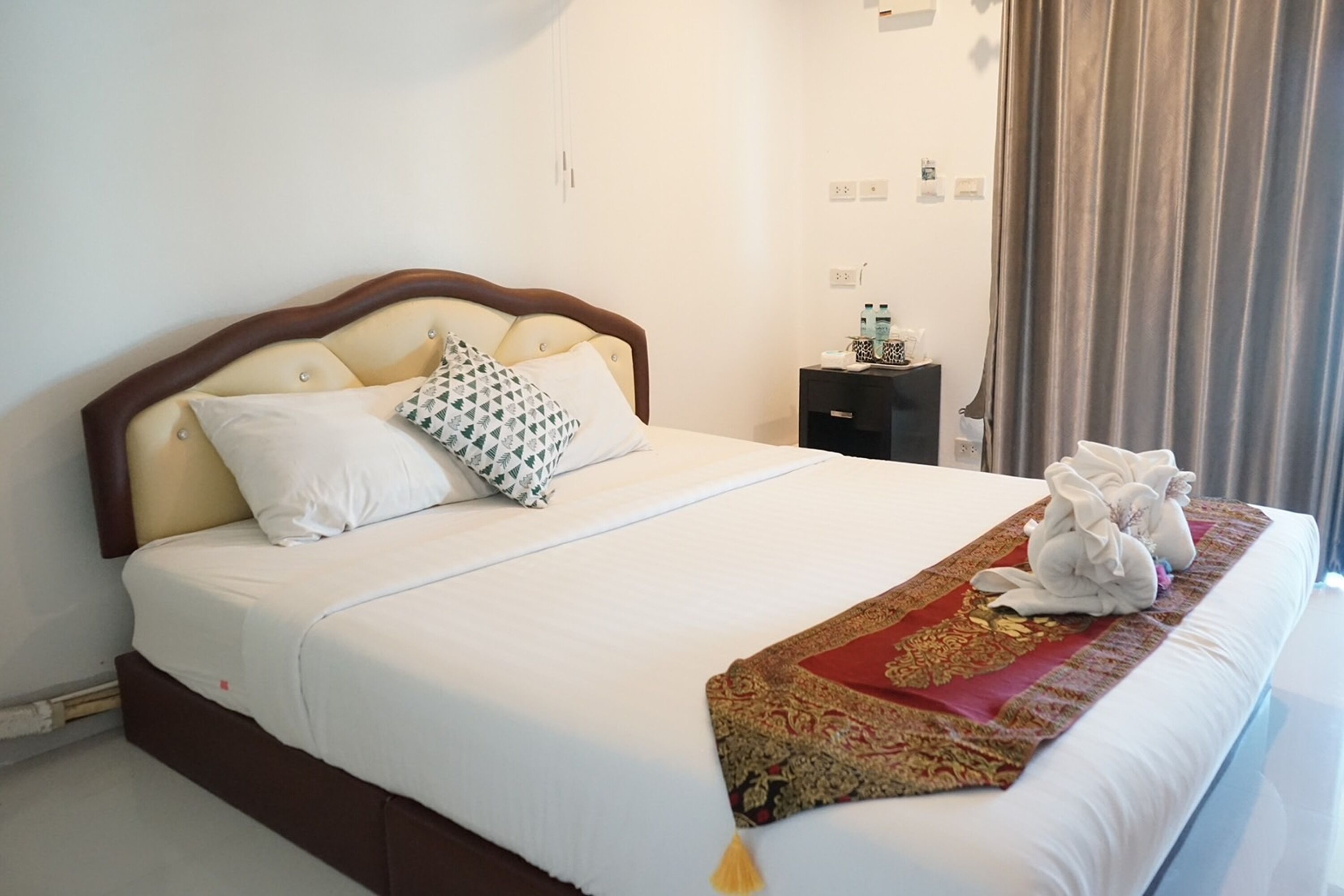 Cama bem arrumada com edredom branco e manta decorativa vermelha e dourada.