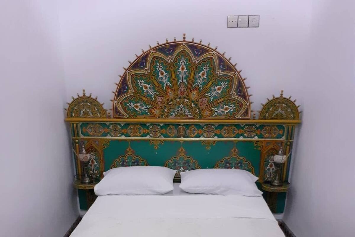 Cama com cabeceira decorativa e piso estampado.