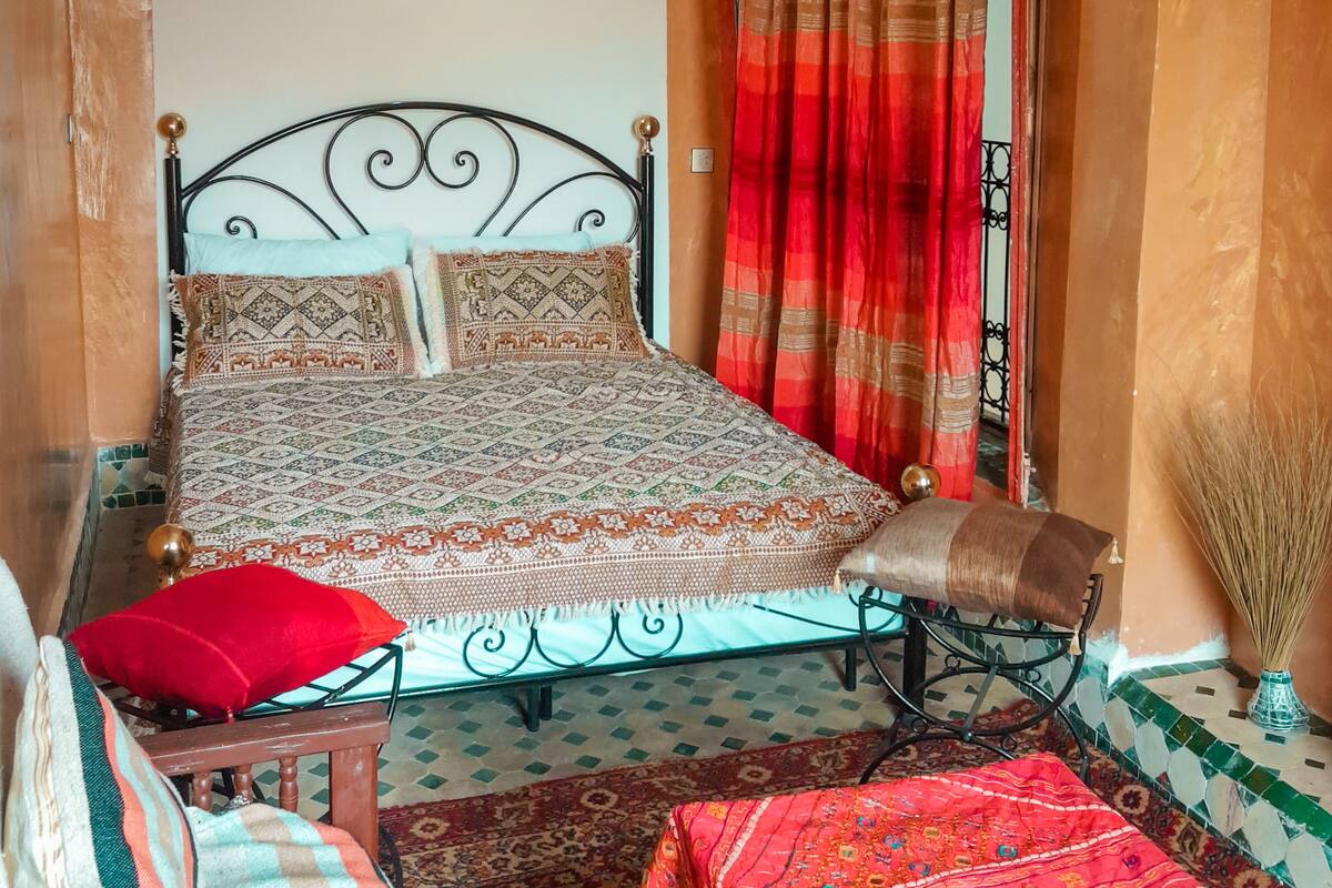 Quarto com cama, cadeira, mesa e decoração na parede.