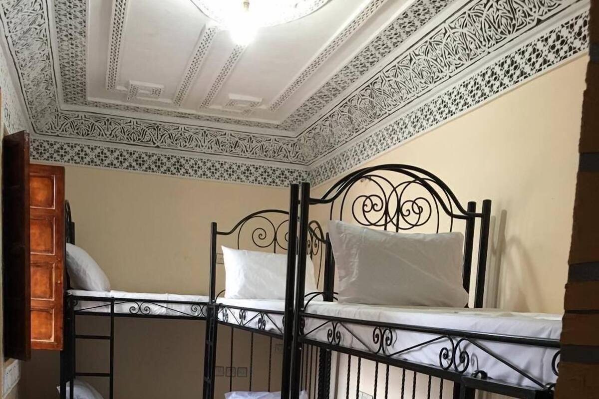 Quarto com três beliches, um tapete estampado e teto decorado.