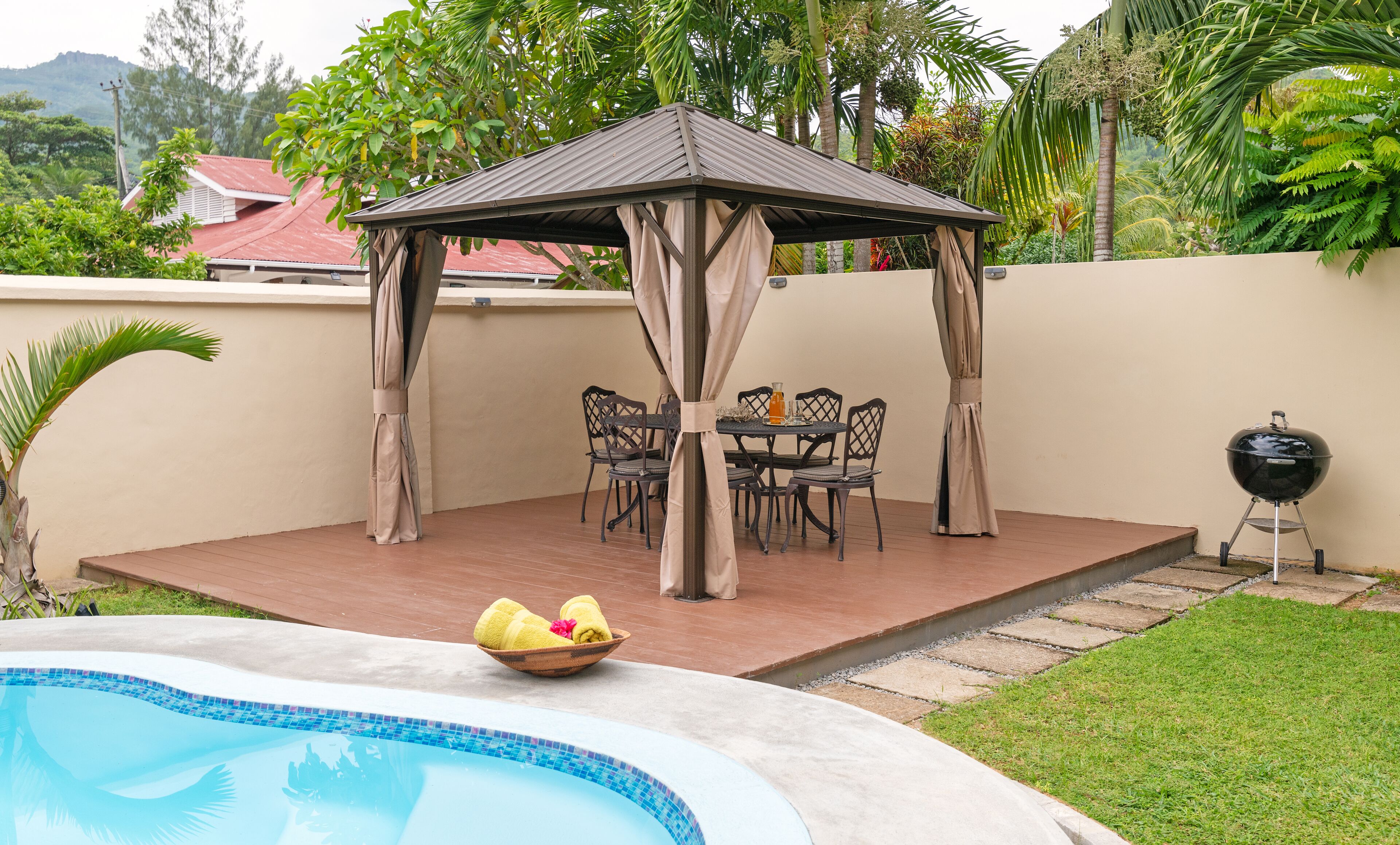 Um alpendre coberto com piscina, móveis de exterior e churrasqueira.