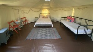 Uma tenda com uma cama, uma mesinha com cadeiras e um sofá.