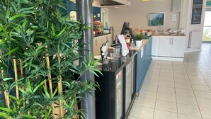 Um café moderno e limpo, com balcão, área de estar e plantas decorativas.