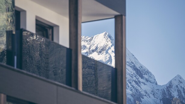 Um edifício moderno com varanda com vista para uma montanha coberta de neve.