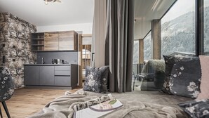 Quarto moderno com cama grande, escrivaninha embutida e vista para uma montanha nevada.