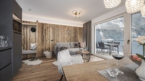 Uma sala de estar moderna com parede de madeira, um sofá, uma mesa de jantar e vista para o exterior.