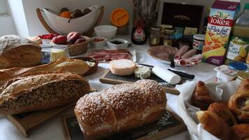 Diversos pães, queijos e carnes sobre uma mesa.