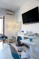 Uma sala de estar moderna com televisão de tela plana, um sofá, uma mesa de jantar e um abajur.