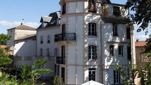 Um edifício grande e branco com telhado íngreme e uma torre imponente.