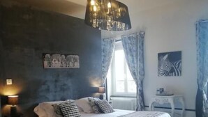 Quarto moderno com cama grande, luminária pendente e obras de arte nas paredes.