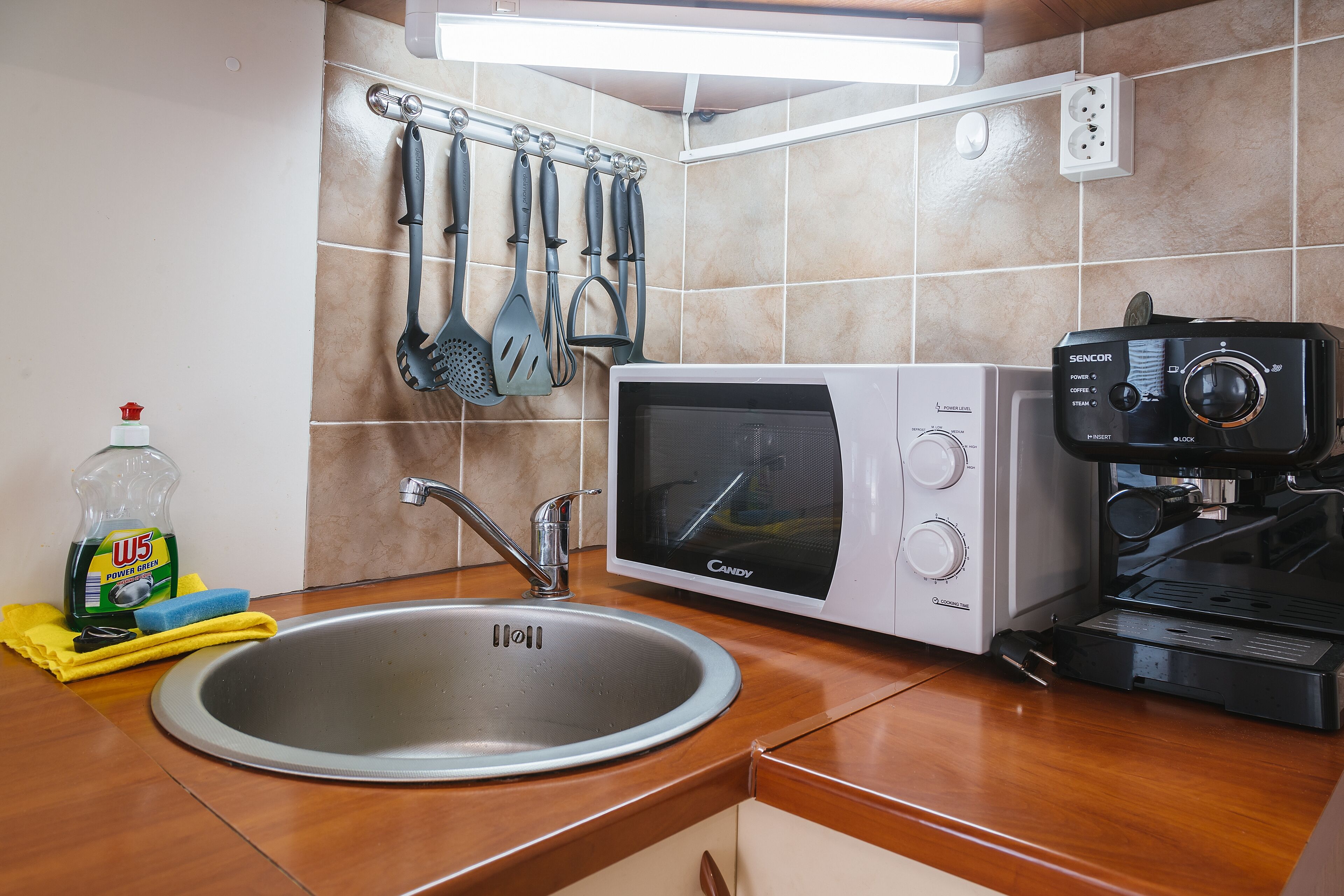 Uma cozinha com pia, micro-ondas e cafeteira.