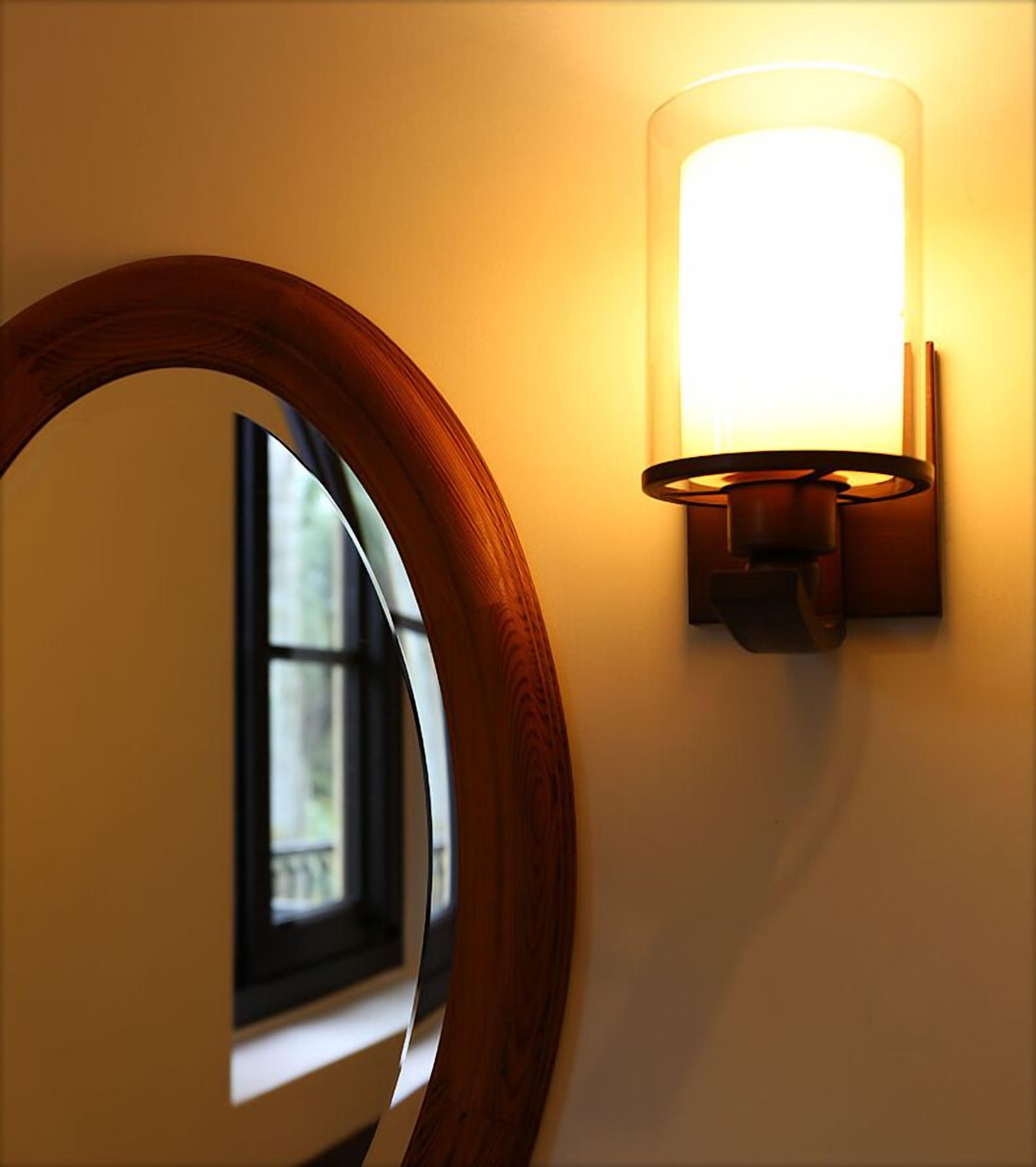 Uma luminária fixada na parede e um espelho.
