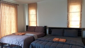Quarto de hotel com duas camas, cada uma com cabeceira e almofadas, e uma janela com cortinas.