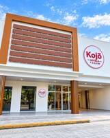 Entrada moderna de um hotel com uma grande placa exibindo o nome 'Kojo Hotels Tagum'.