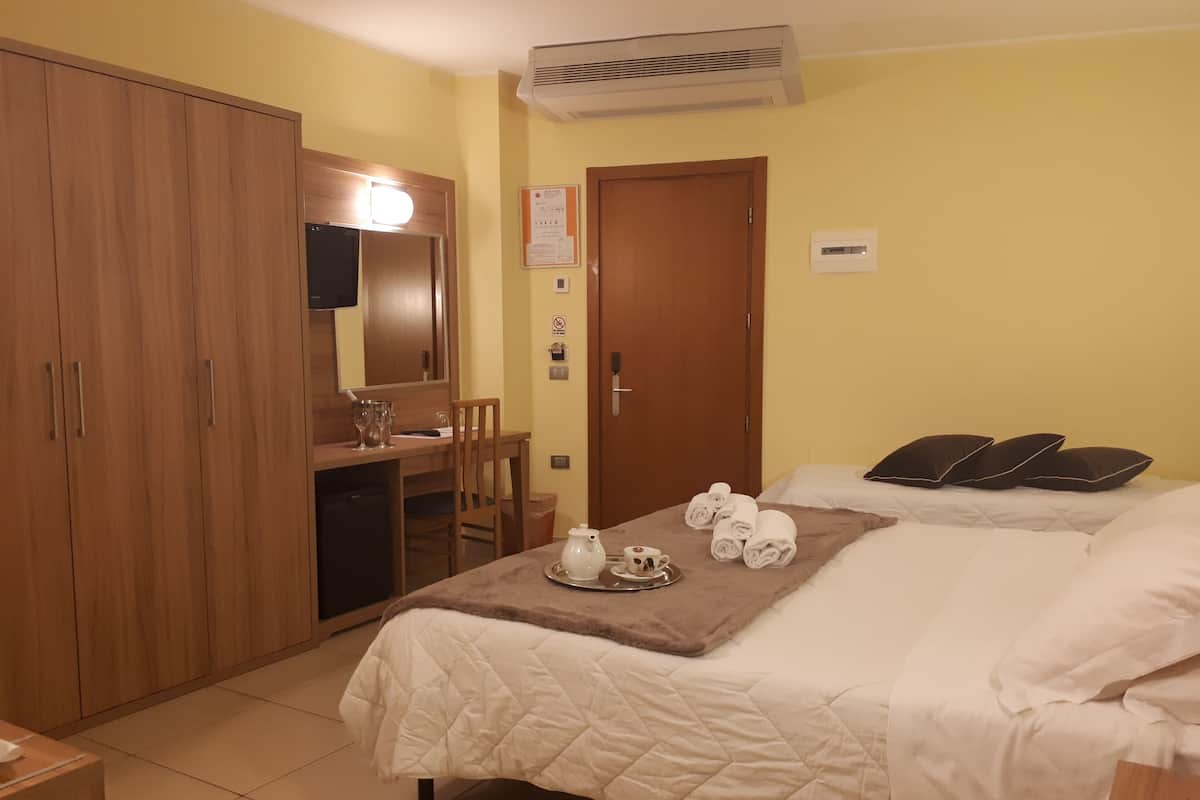 Quarto de hotel com cama, escrivaninha, cadeira e armário.