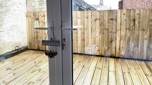 Um deck de madeira com um portão de metal e uma placa que diz 'Beautiful Garden'.