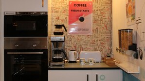 Cozinha com micro-ondas, máquina de café, torradeira e placa com a palavra café.