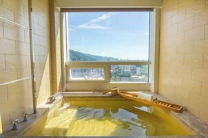 Uma banheira com vista para o horizonte urbano através de uma grande janela.