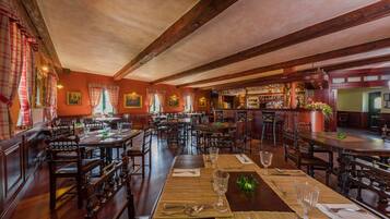 Restaurante com mobiliário de madeira, área de bar e paredes vermelhas.