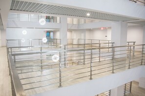 Amplo espaço interior com vários níveis, grades de metal e um espaço aberto central.