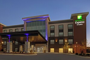 Um hotel Holiday Inn Express & Suites com design moderno, destacando uma entrada imponente e uma área externa coberta.
