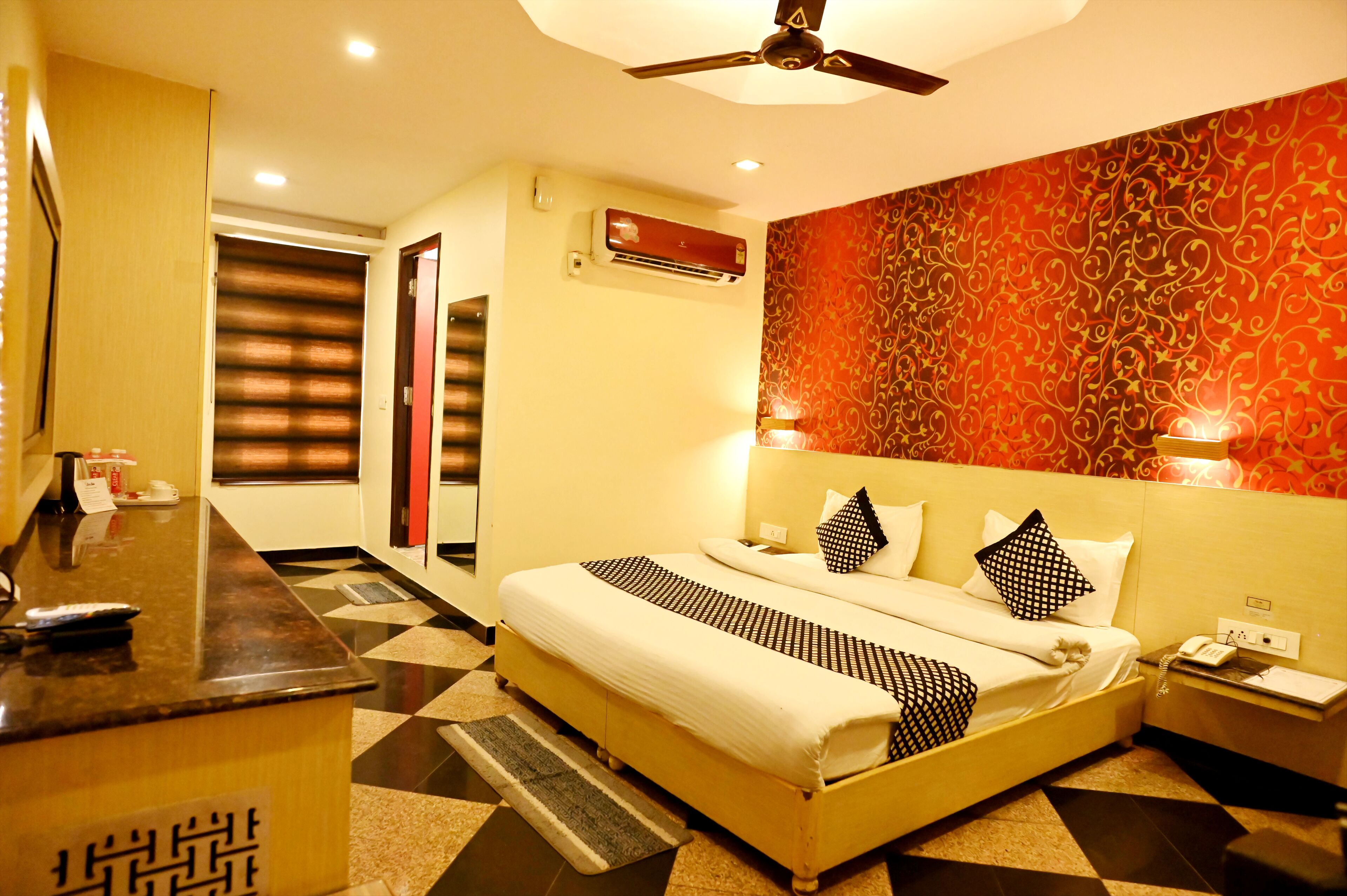 Quarto de hotel com cama, mesa de cabeceira e escrivaninha com telefone.