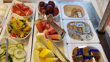 Buffet com diversas frutas, legumes e lanches embalados.