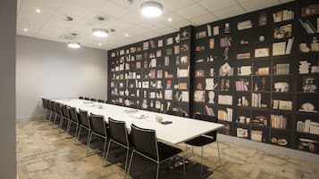 Uma sala de conferências com uma mesa comprida, cadeiras e uma parede com estantes.